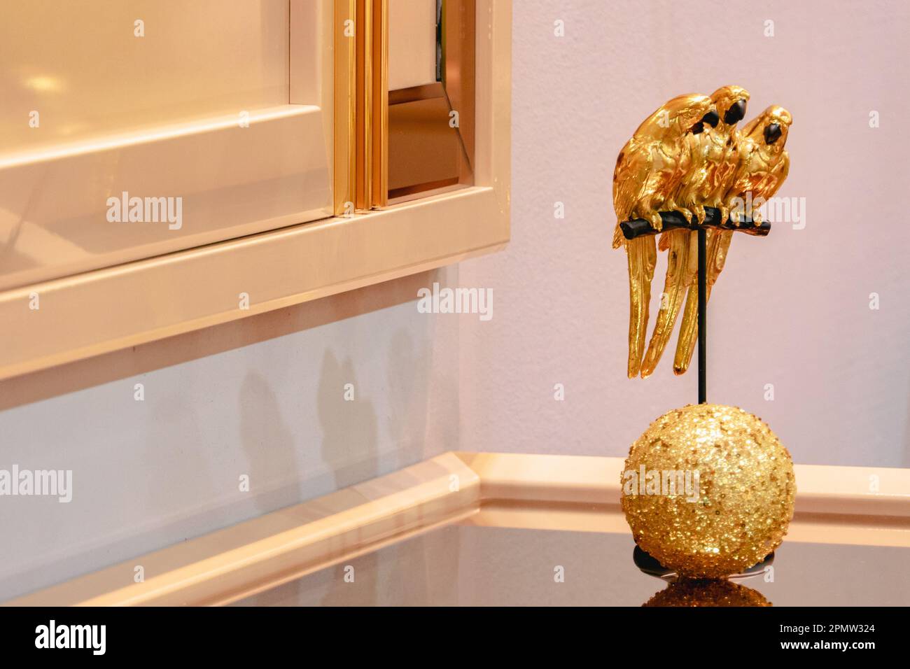 Figurine Three golden parrots on a perch in the interior of the room ...