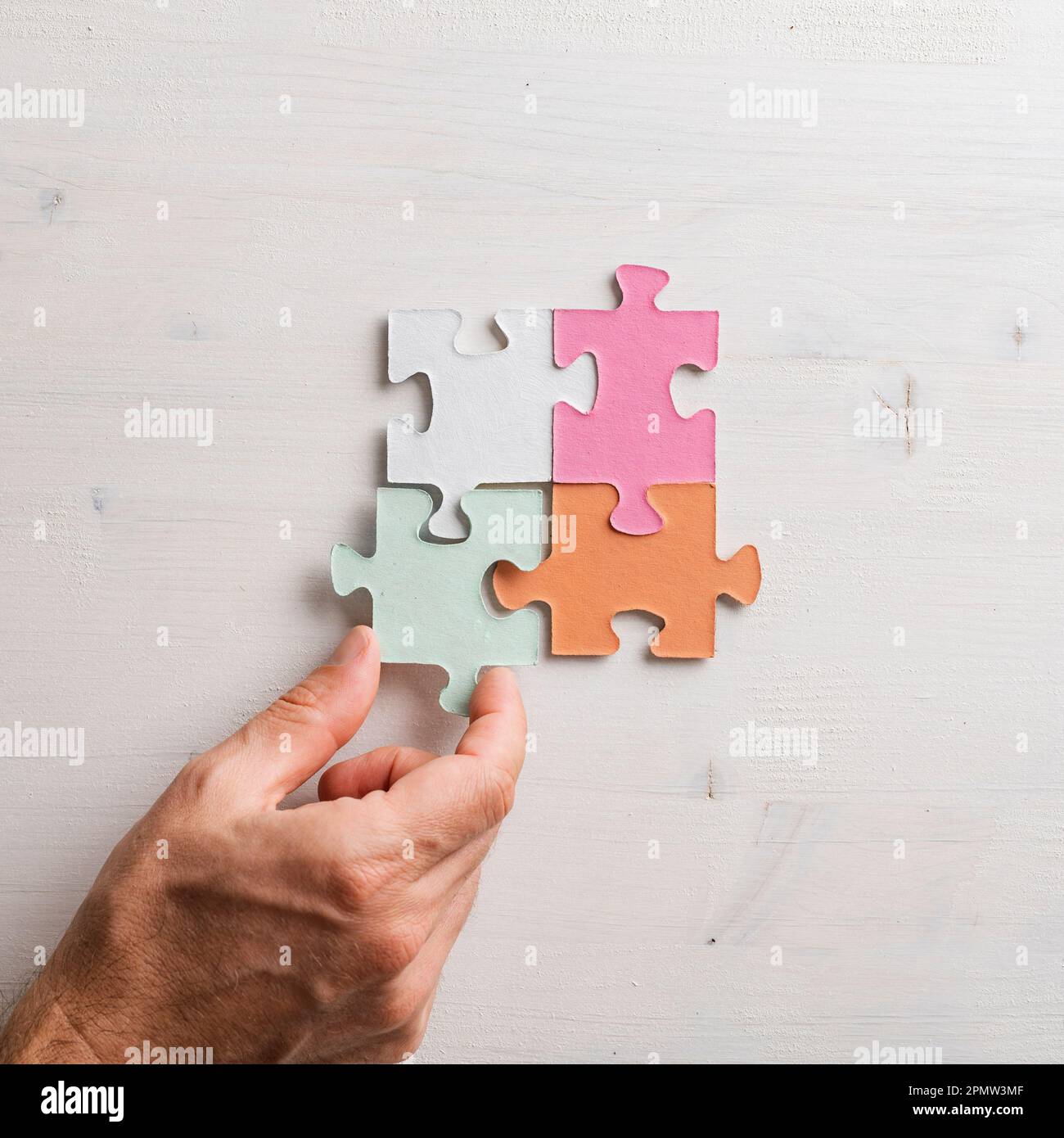 Top view of male hand joining four matching colorful puzzle pieces over ...