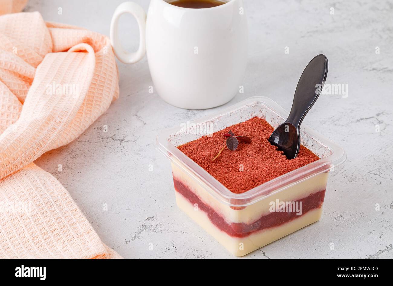 Tiramisu dessert in a plastic box with a fork on a concrete background ...