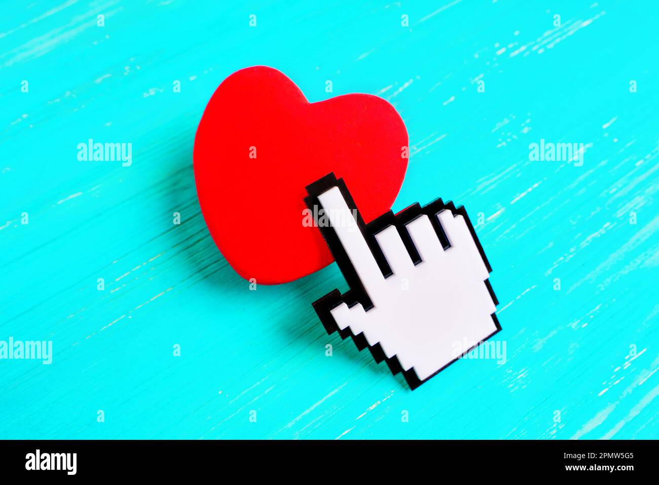 Large pixelated hand-shaped cursor touches a red heart placed on a ...