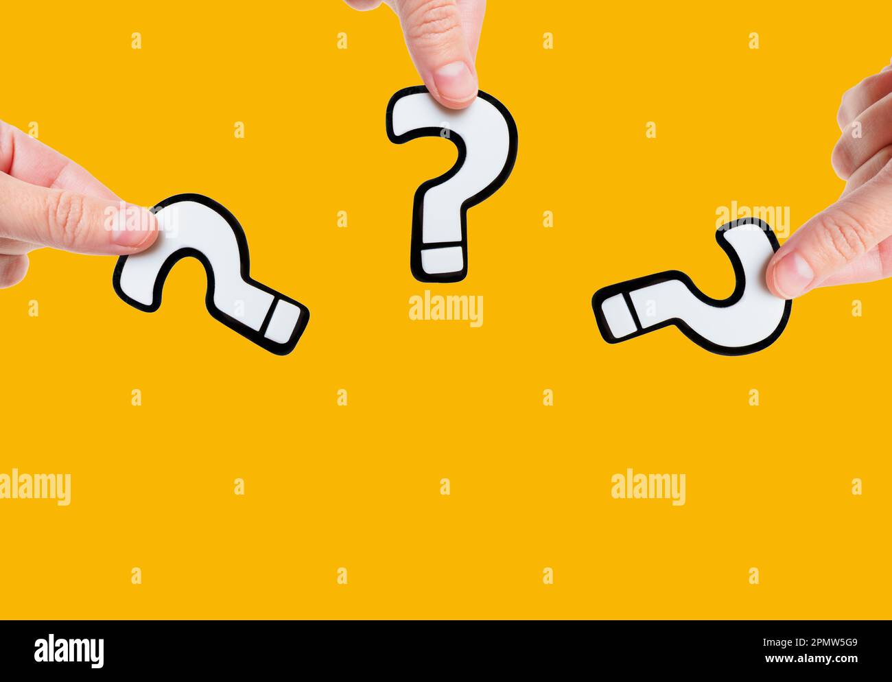 Close-up view of three white and black plastic question marks in hands isolated on plain yellow ...