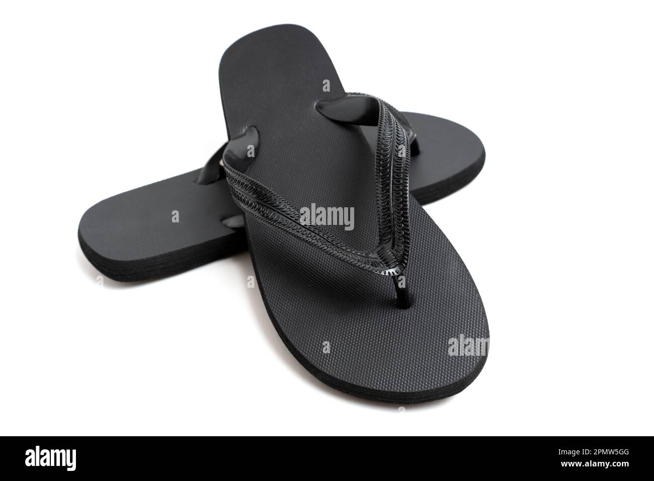 A close-up studio shot of a pair of black flip-flops isolated against a ...