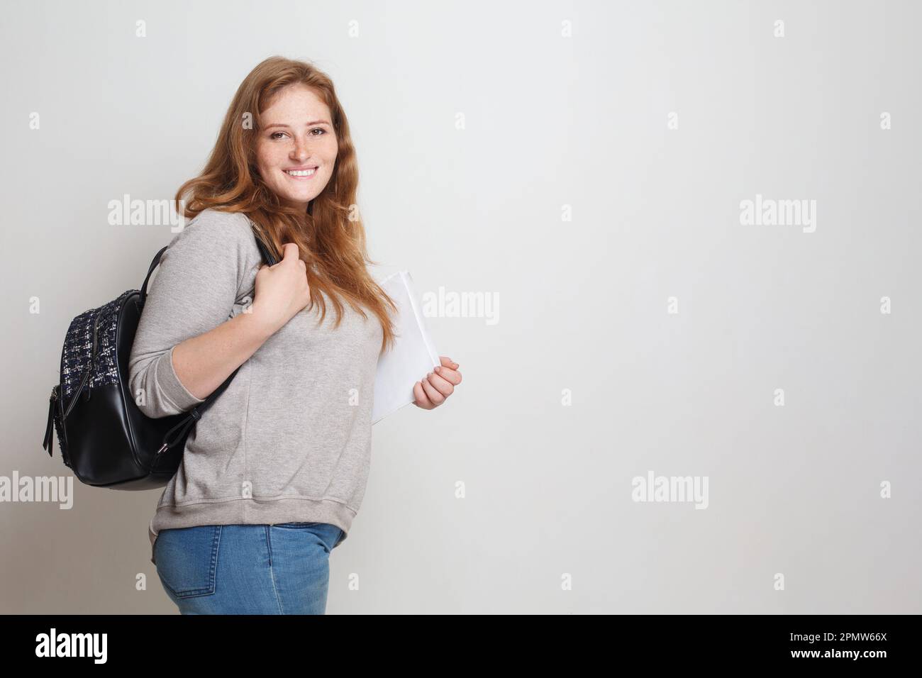 Happy student woman standing against white studio wall banner ...