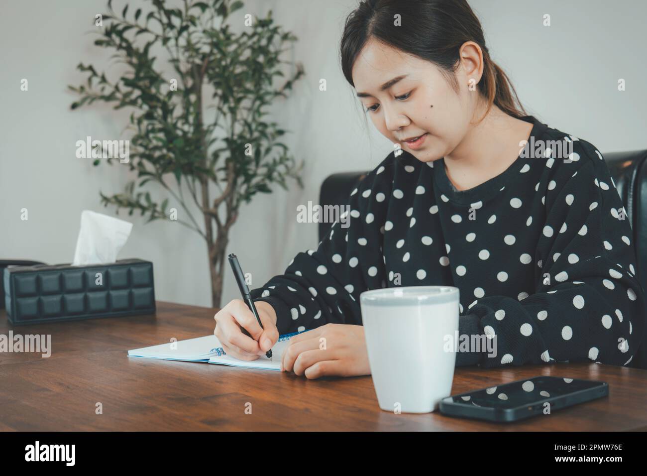 Young asian woman pupil writing notes in notebook at work table ...