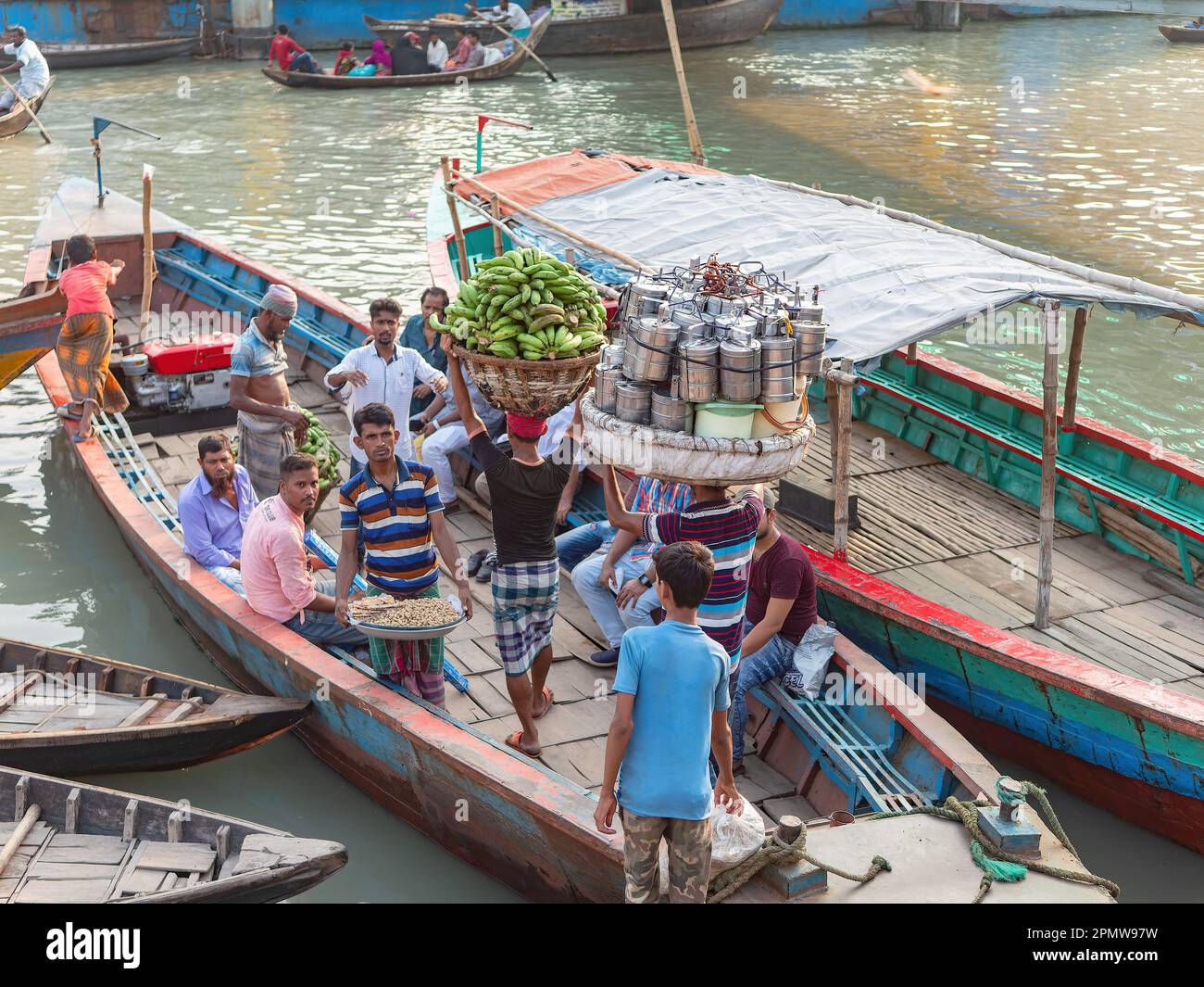 Men carrying bunches of green bananas and other products to local ...