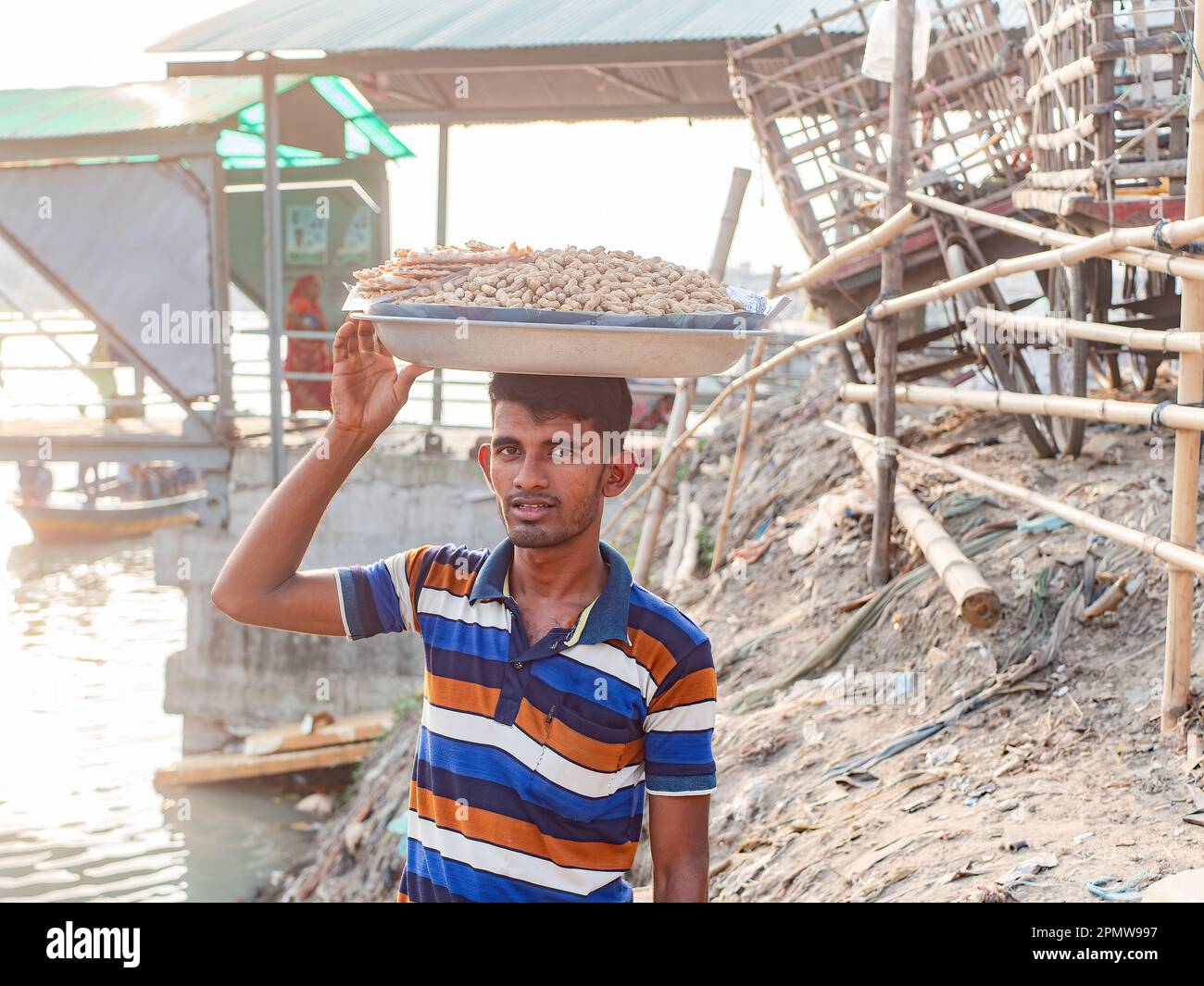 Man carrying tray of peanuts to local ferries at Wise Ghat Boat Station ...