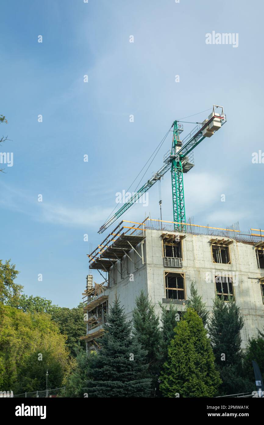 A tall crane stands by a building under construction Stock Photo - Alamy