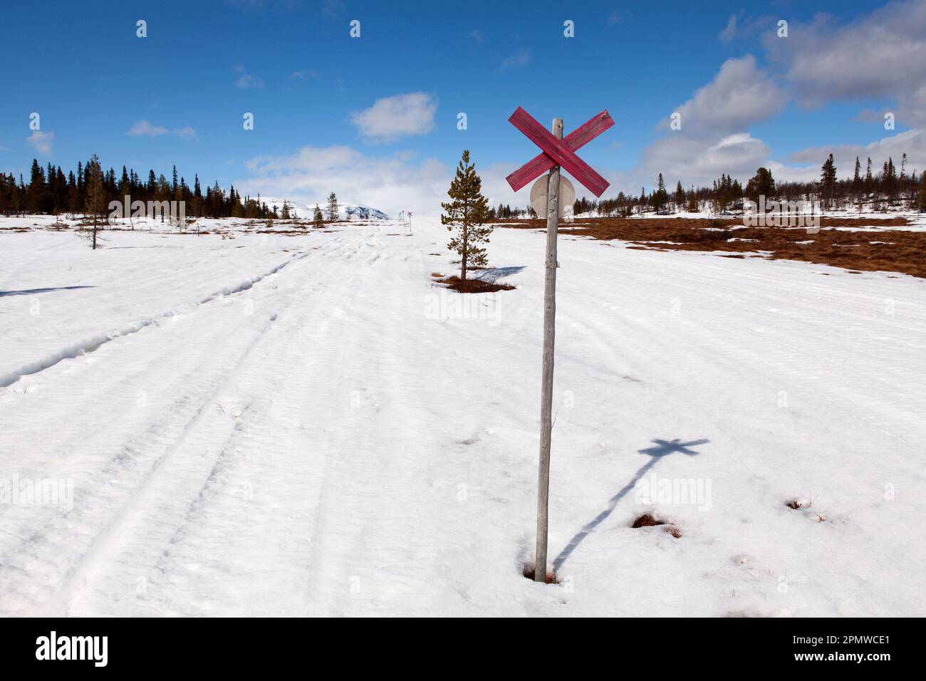 Snowmobile trail, tracks, and signs in the snow, springtime. Tussock ...