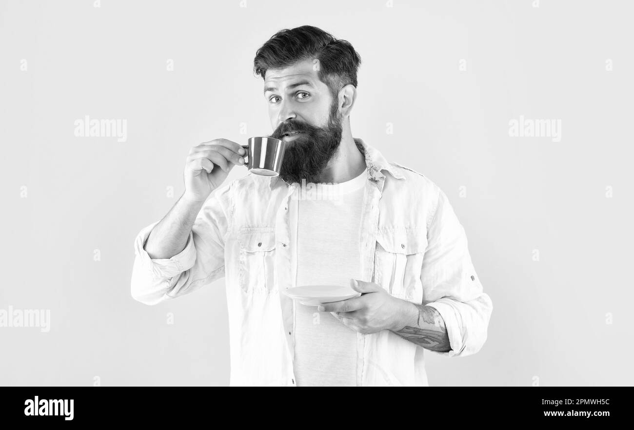 Serious caucasian guy drinking coffee from cup holding saucer yellow ...