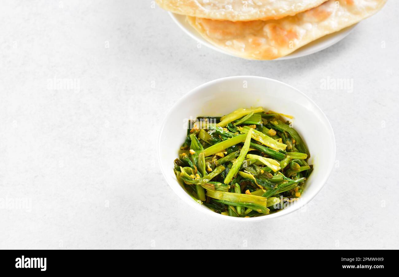 Indian style spring onion stir fry in bowl over white background with ...