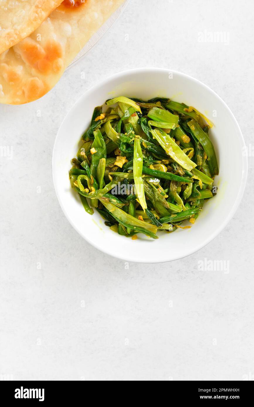 Indian style spring onion stir fry in bowl over white background with ...