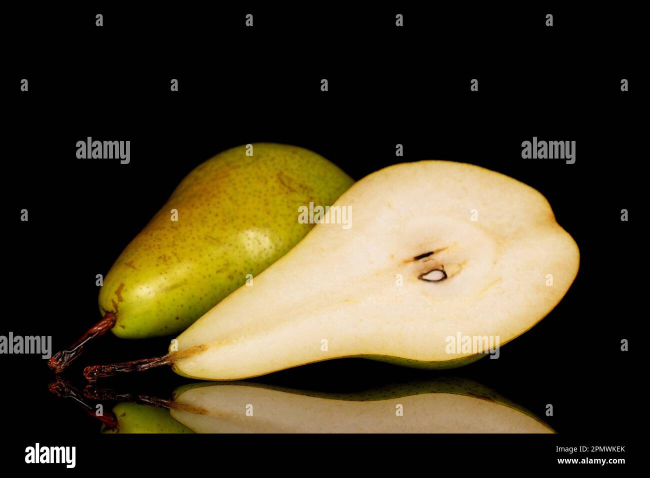 One whole and one half ripe organic pear, macro, on black background ...