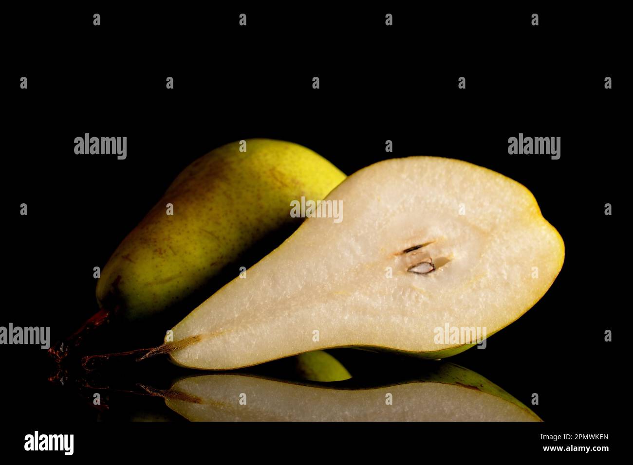 One whole and one half ripe organic pear, macro, on black background ...