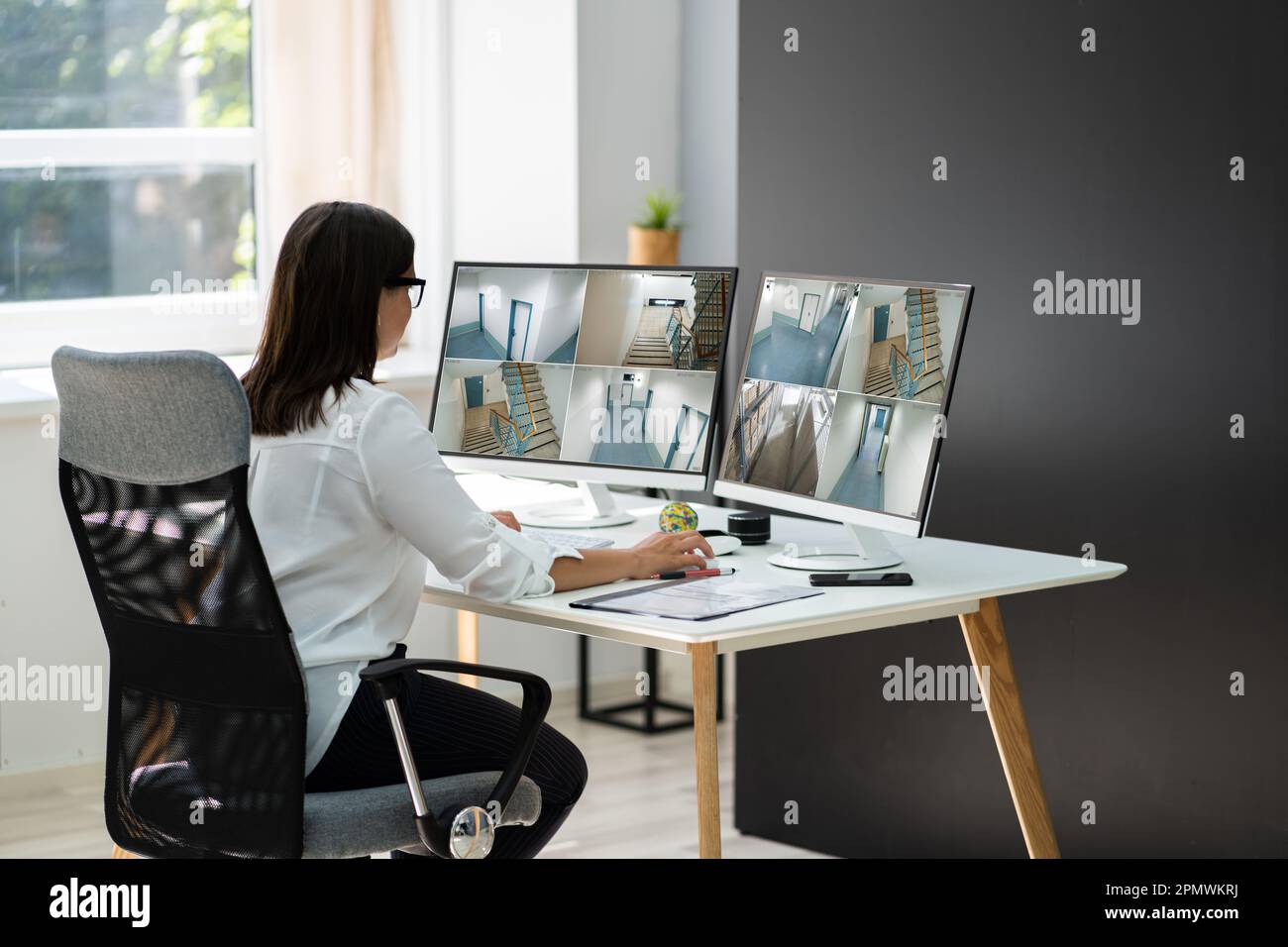 Businesswoman Watching CCTV Footage Of Office Interior On Computer At ...