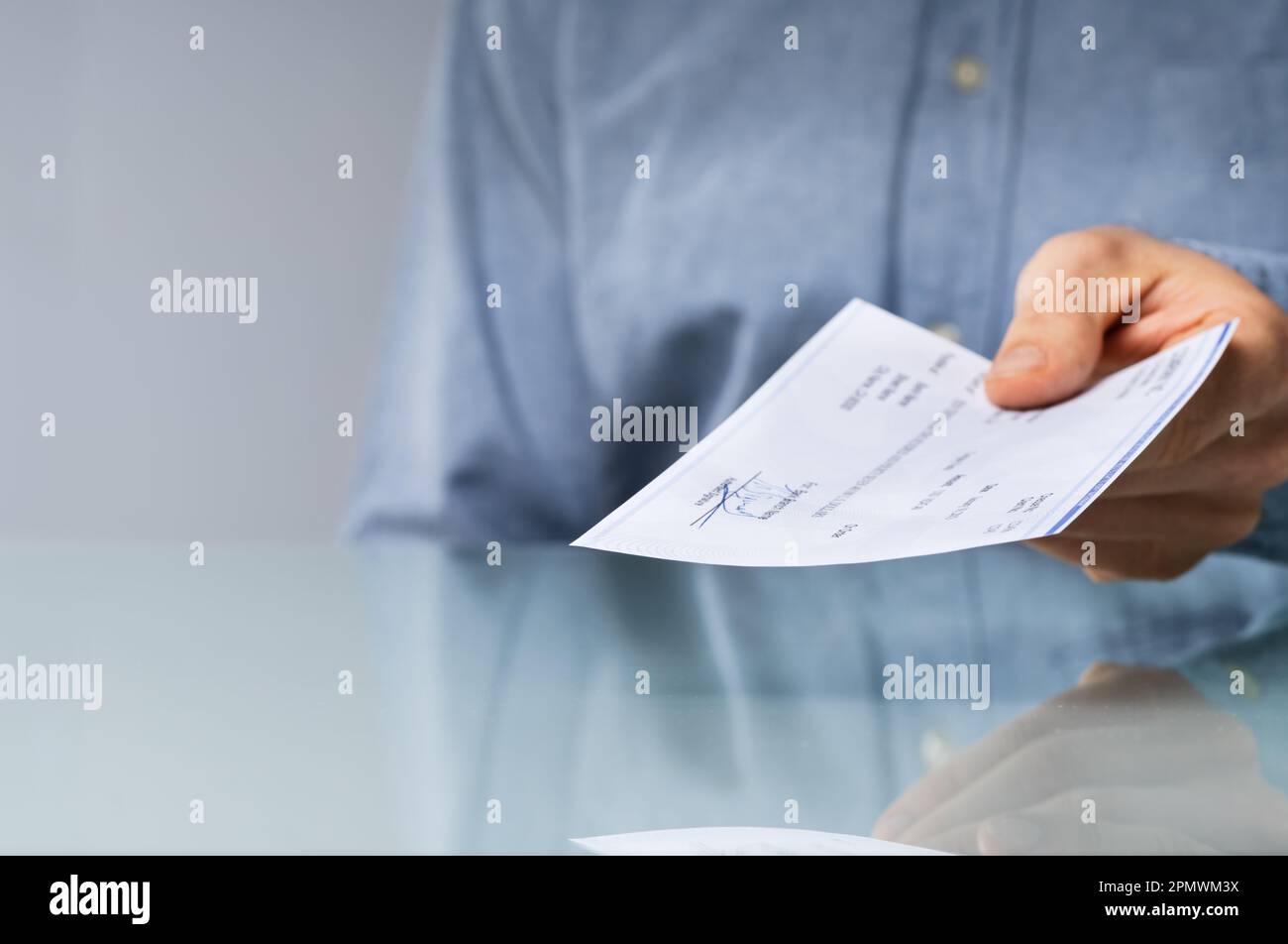 Close-up Of A Human Hand Giving Cheque On Desk Stock Photo - Alamy
