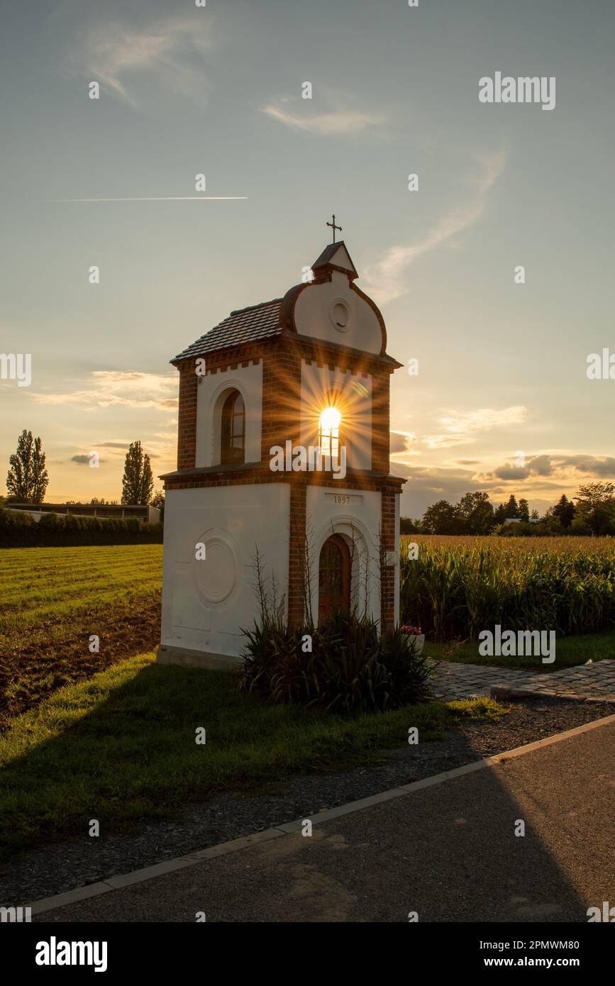 A vertical shot of a historic two-story chapel with the sun shining ...