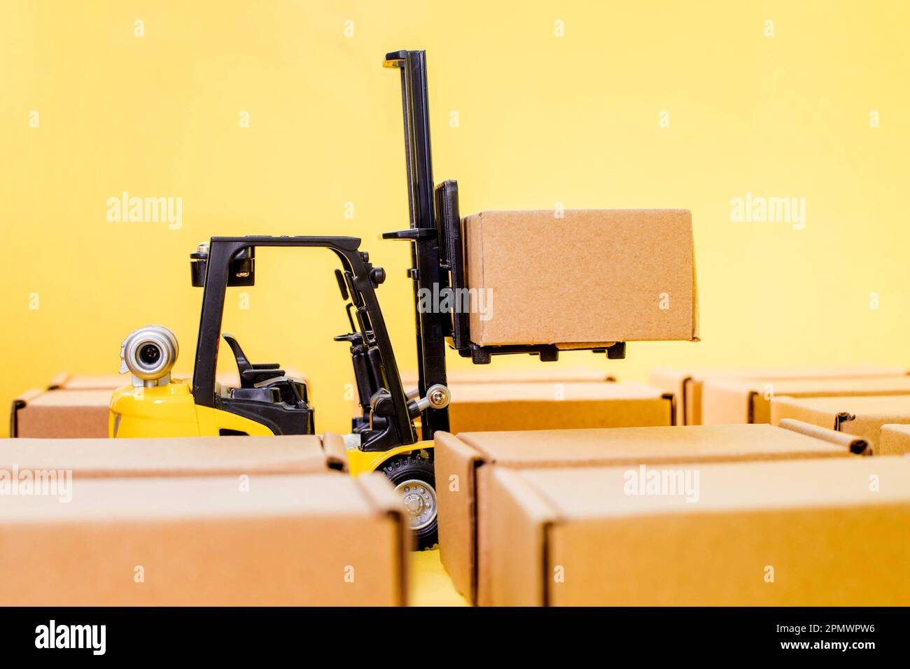 Forklift truck raises cardboard boxes on a yellow background. Cargo ...