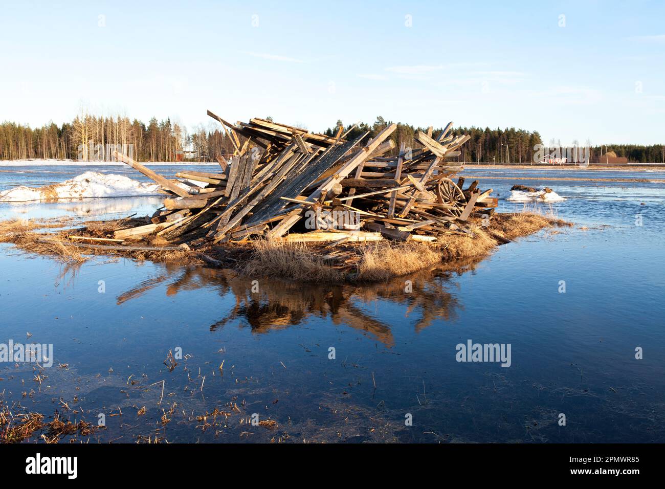 Demolished barn in flooded area. Planks, log, and debris in a pile ...