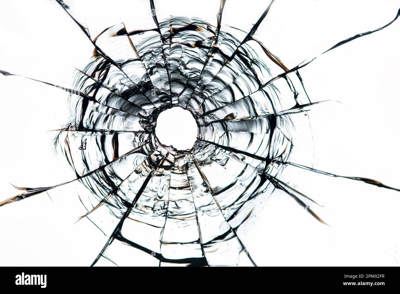 glass with visible cracks caused by a bullet impact on a white ...