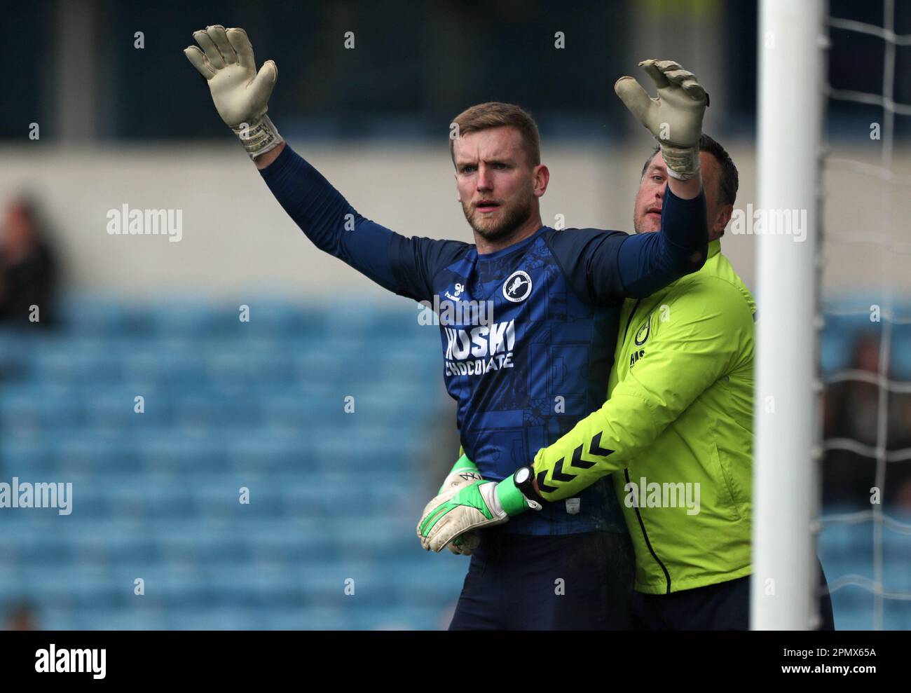 Millwall goalkeeper George Long being held by Millwall goalkeeper coach ...