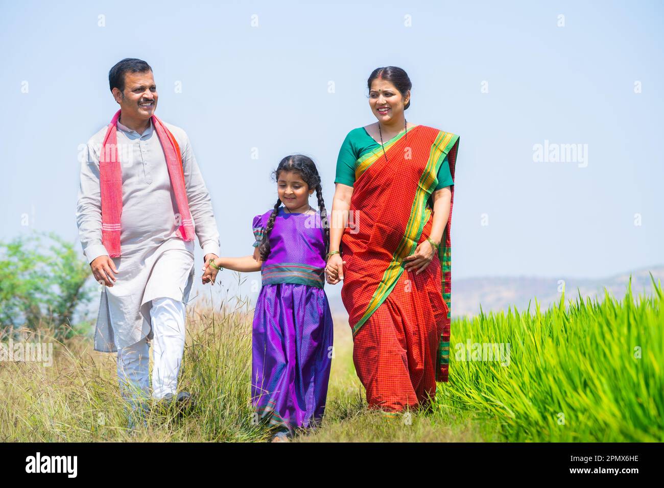 Happy indian village couple with kid walking by talking each other near ...