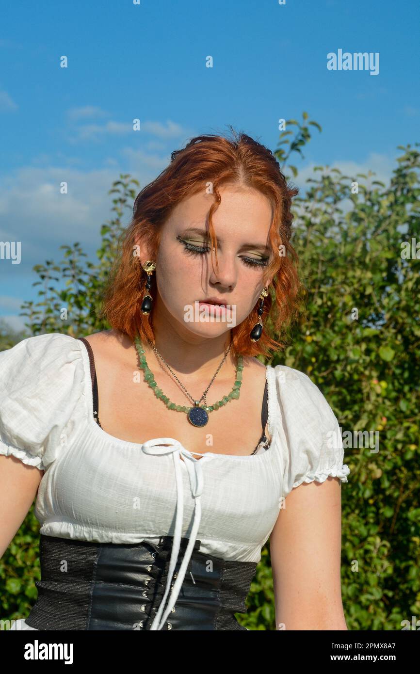 Portrait of a pretty young woman wearing white top, looking down ...