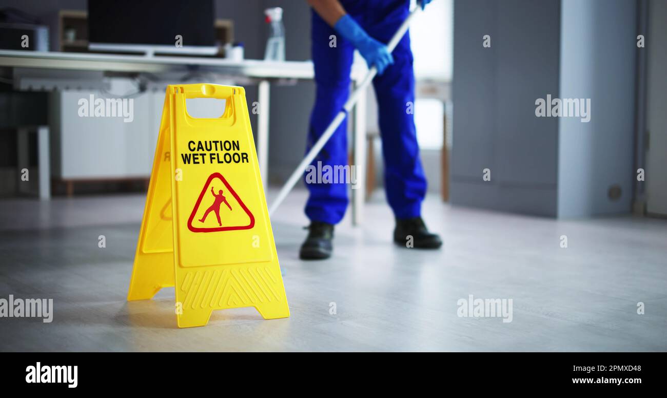 Low Section Of Male Janitor Cleaning Floor With Caution Wet Floor Sign ...