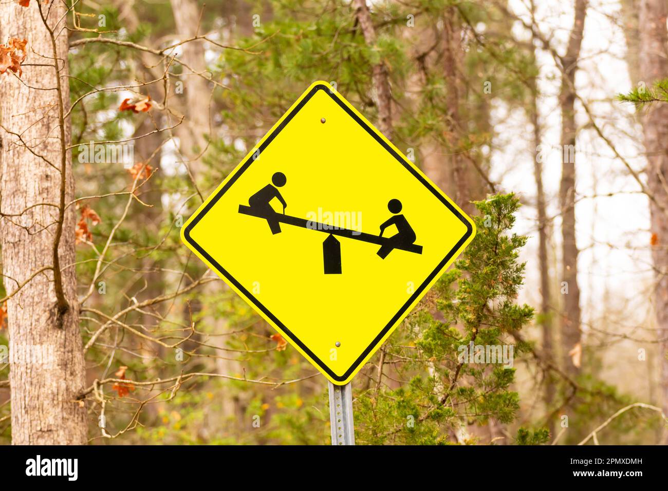 Warning, children at play on a seesaw ride. A black and yellow sigh ...