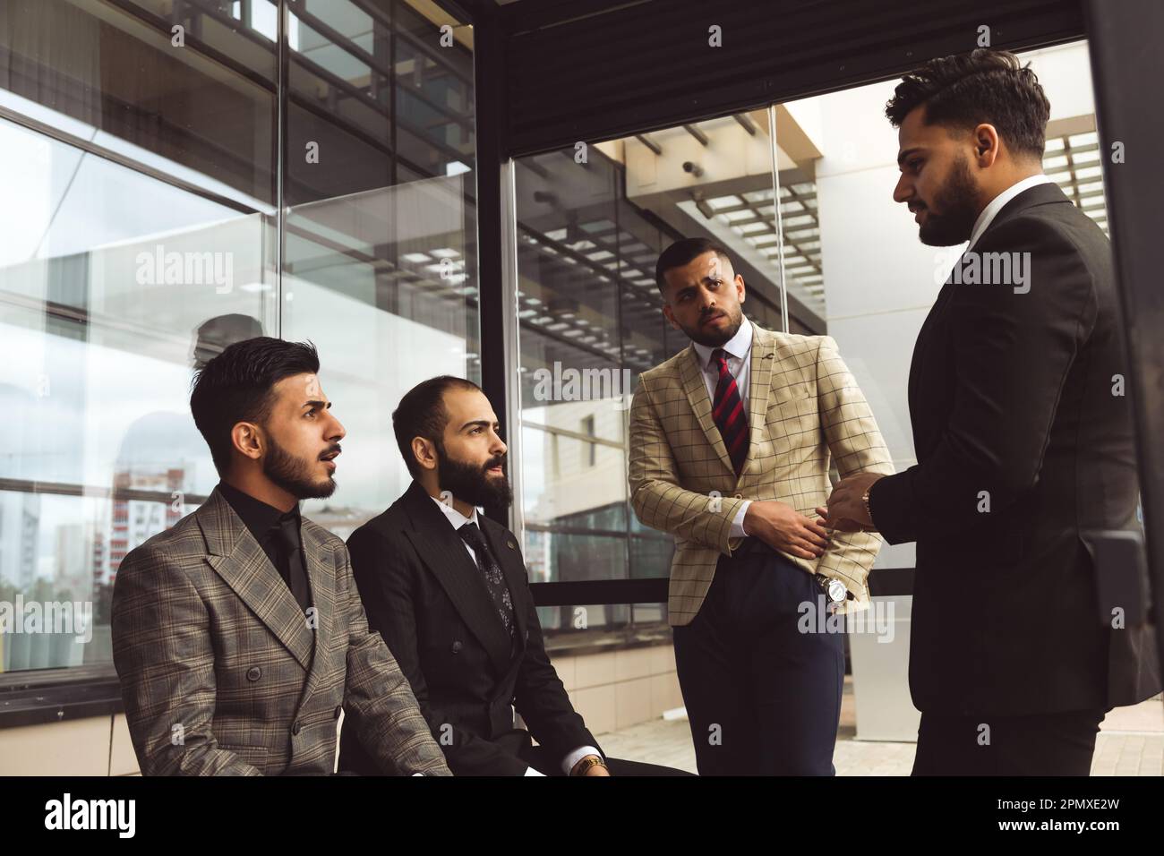 An international team of successful young business men in suits at a meeting are discussing the ...