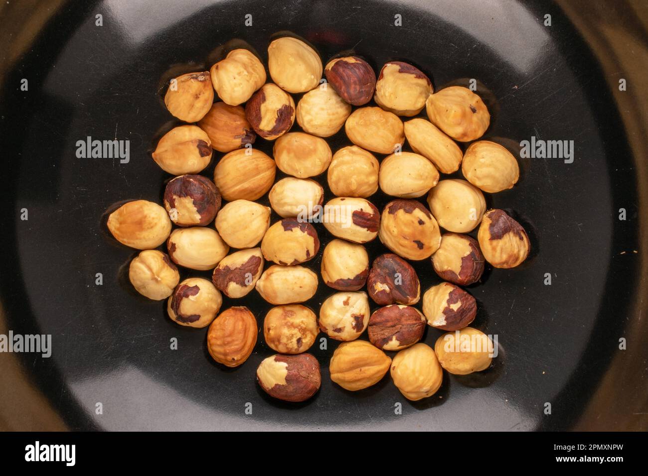 Roasted hazelnuts in a black ceramic dish, macro, top view Stock Photo ...