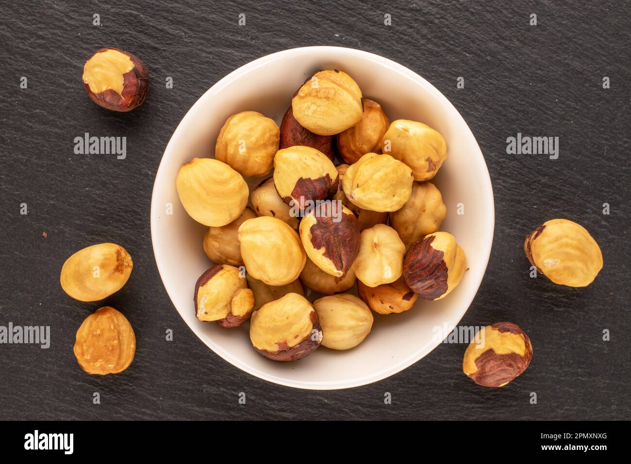 Roasted hazelnuts with white ceramic saucer on slate stone, macro, top ...