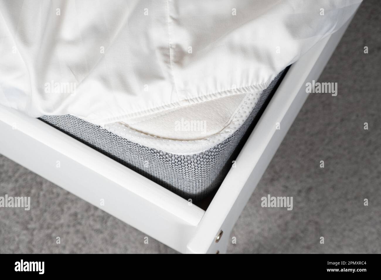 White satin sheet on an elastic band on the mattress. Bed linen on the ...