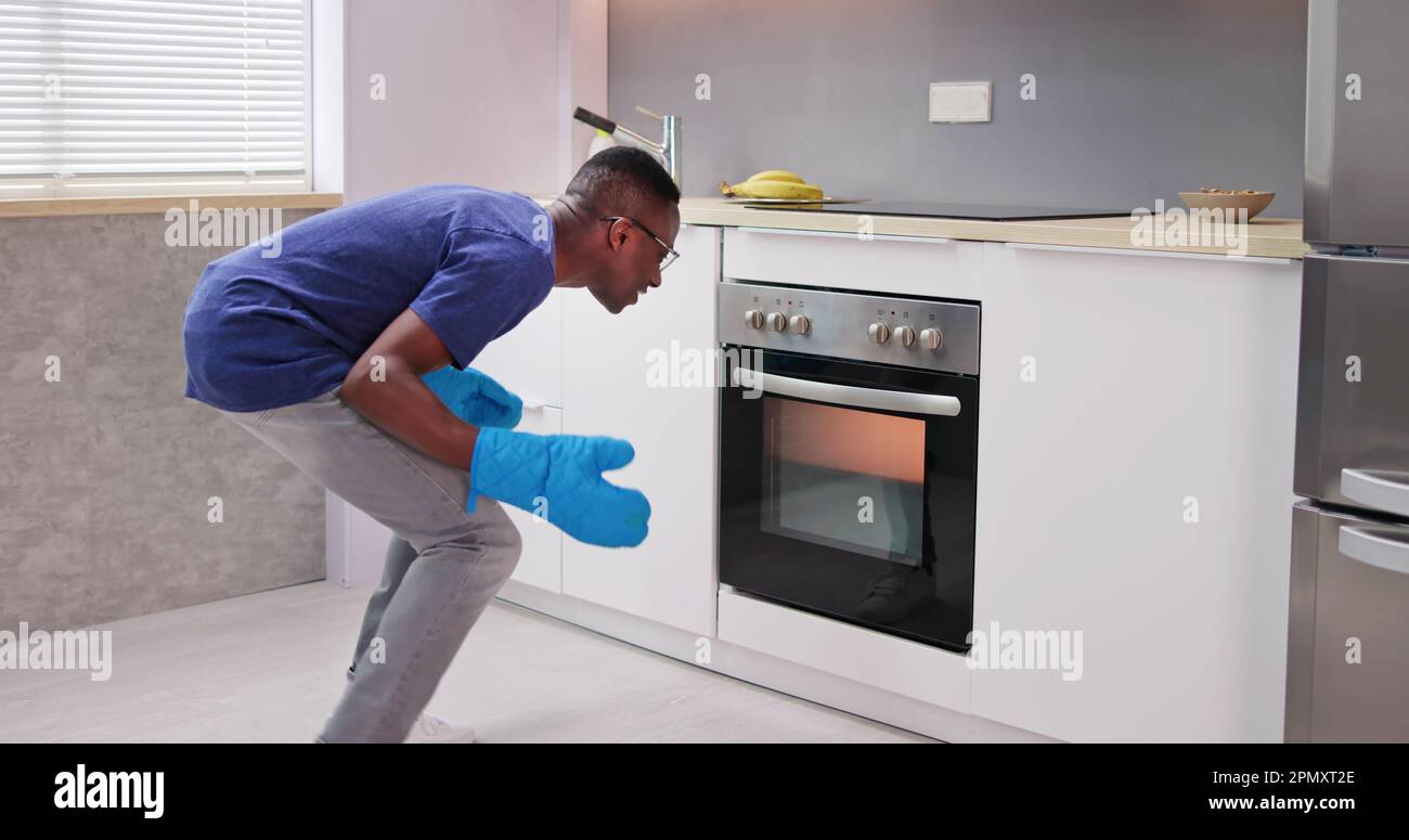 Shocked Young Man Looking At Smoke Coming Out Of Oven In Kitchen Stock ...