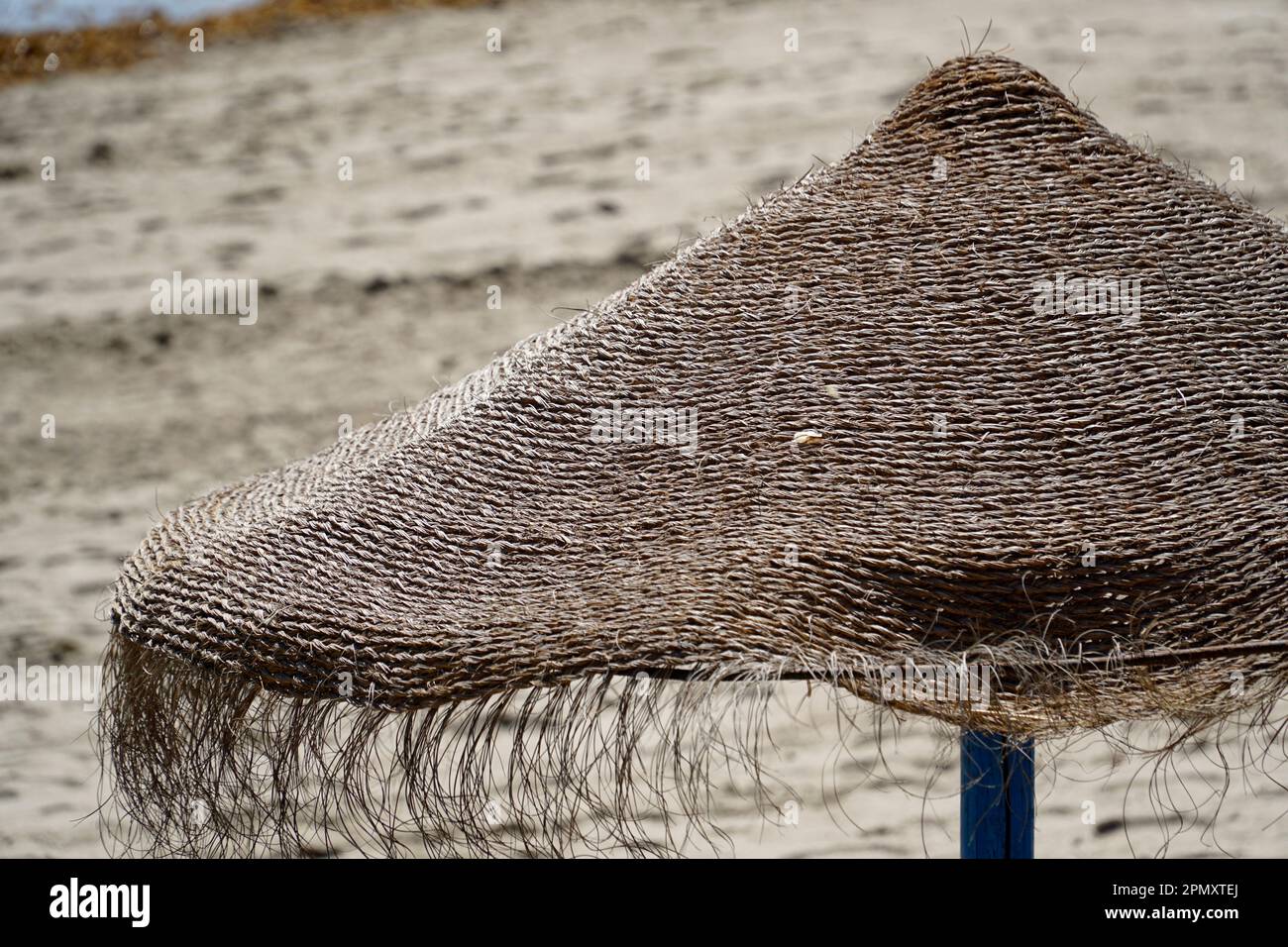 Straw umbrella on sandy beach - close-up Stock Photo - Alamy