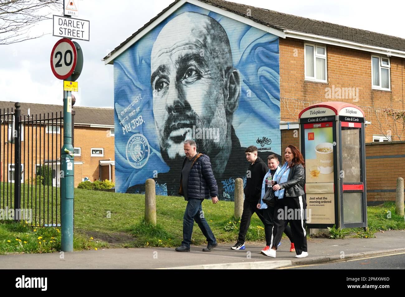 Manchester City fans walk past a mural of Manchester City manager Pep ...