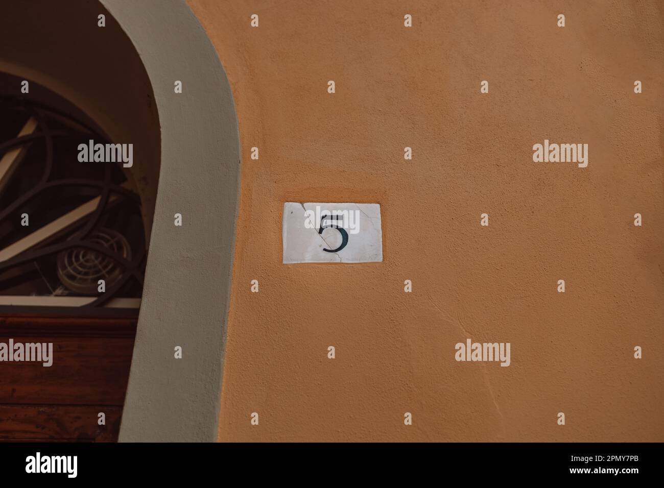 Ceramic house number five 5 house number on orange wall background ...