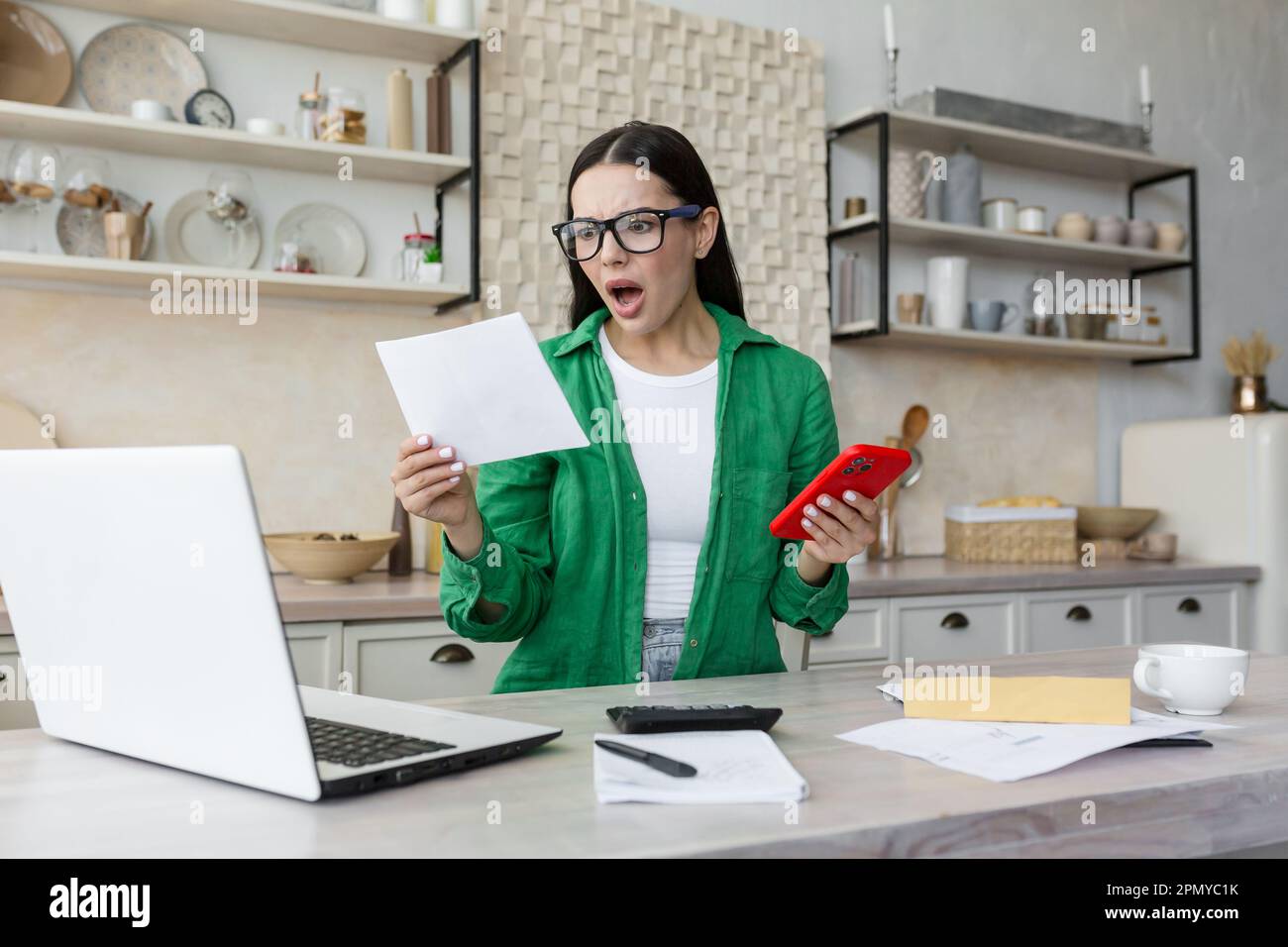 Shocked young woman reading a received letter while sitting in the ...