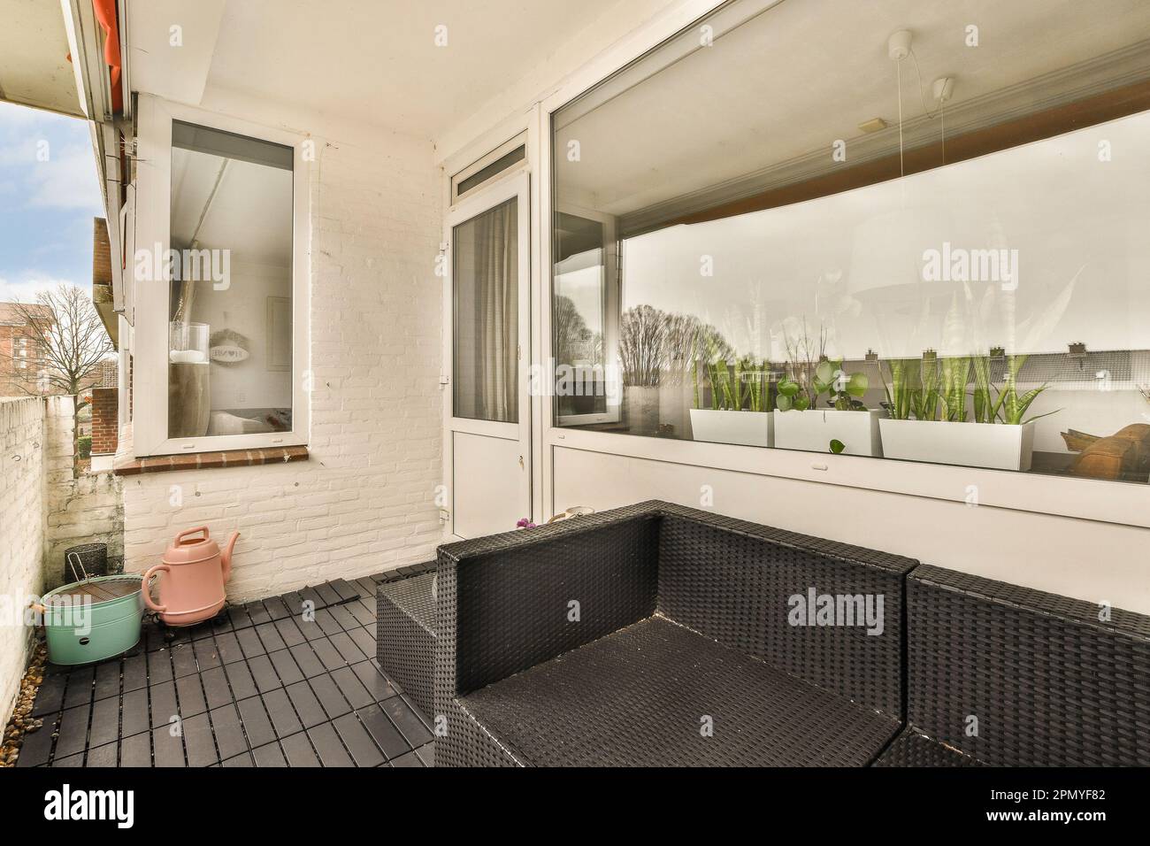 an outside area with furniture and plants in the fore - windowed room ...