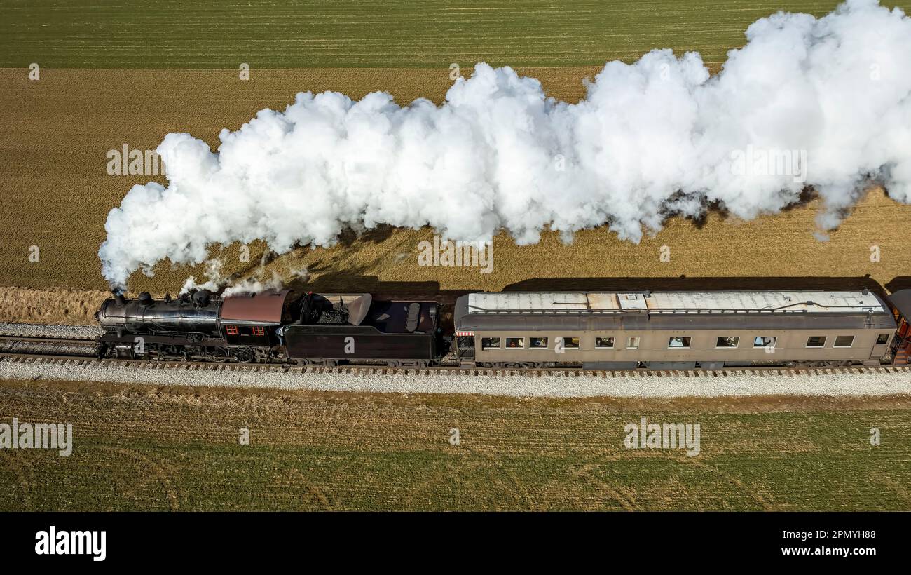 An aerial view of a steam train on tracks through a rural countryside ...