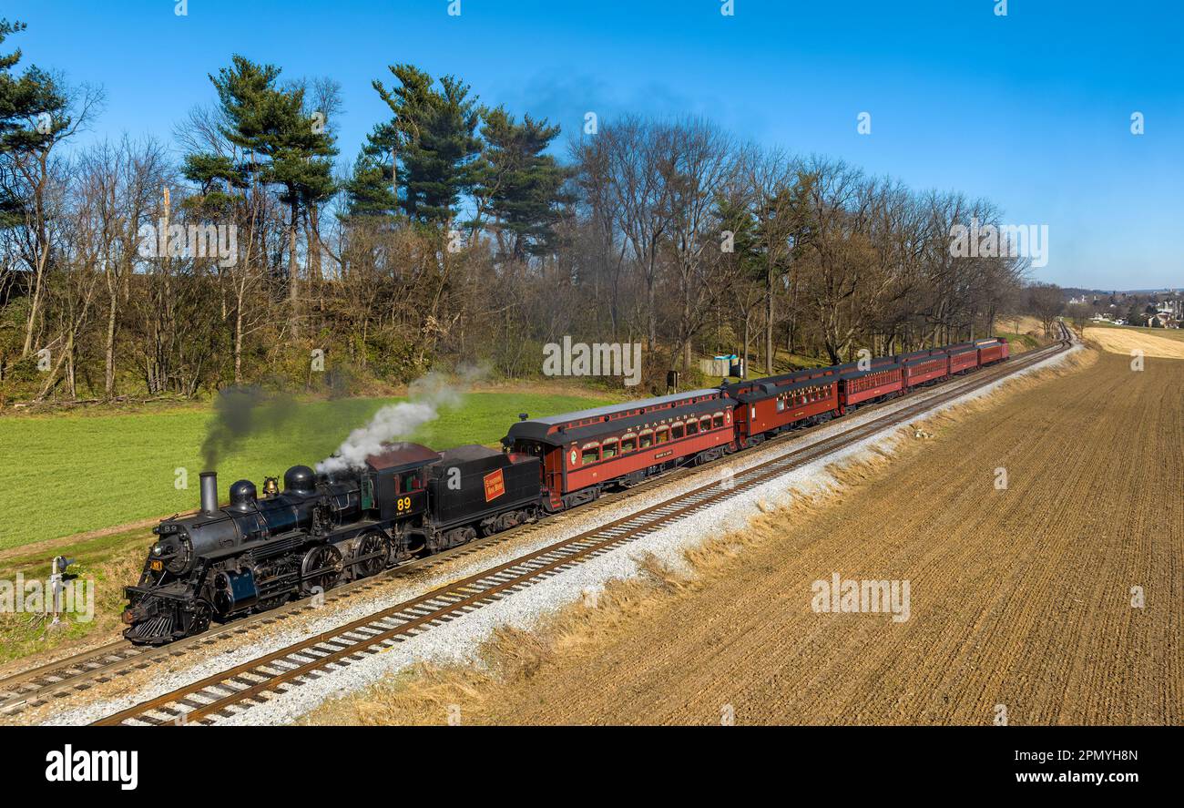 An aerial view of a steam train on tracks through a rural countryside ...