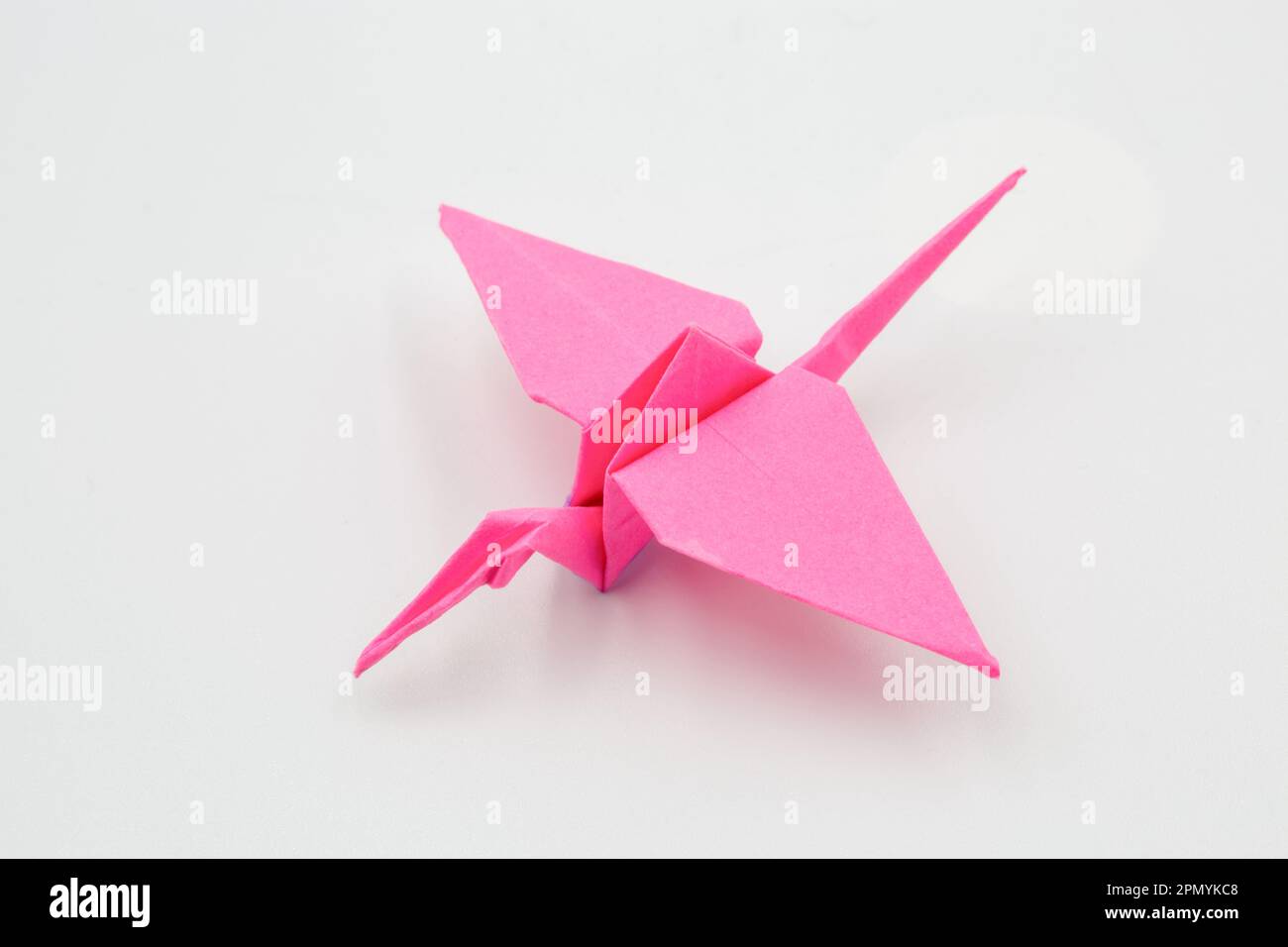 Hand picked pink paper crane origami closeup on white Stock Photo - Alamy