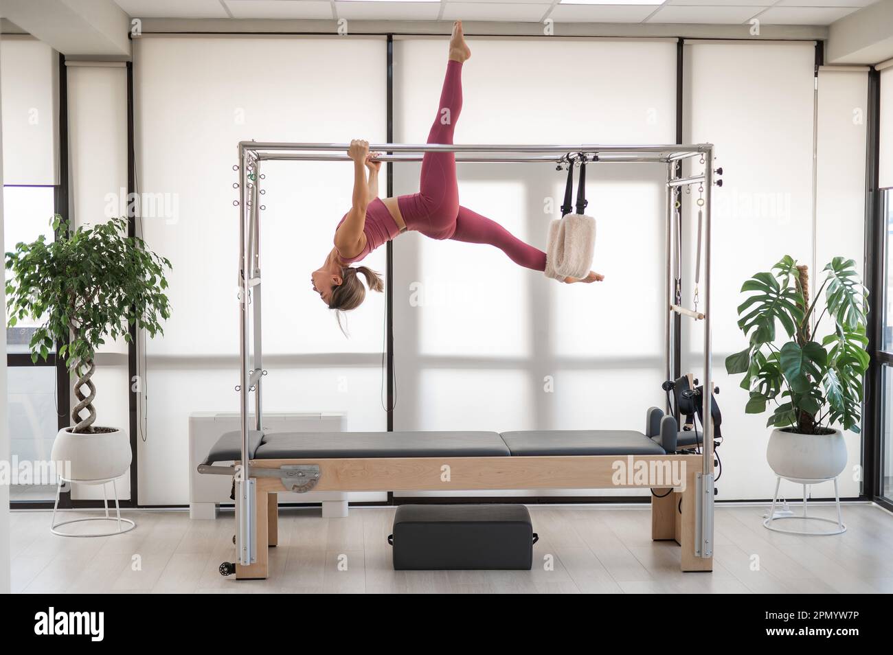 Beautiful asian woman in pink sportswear doing pilates on bed reformer ...