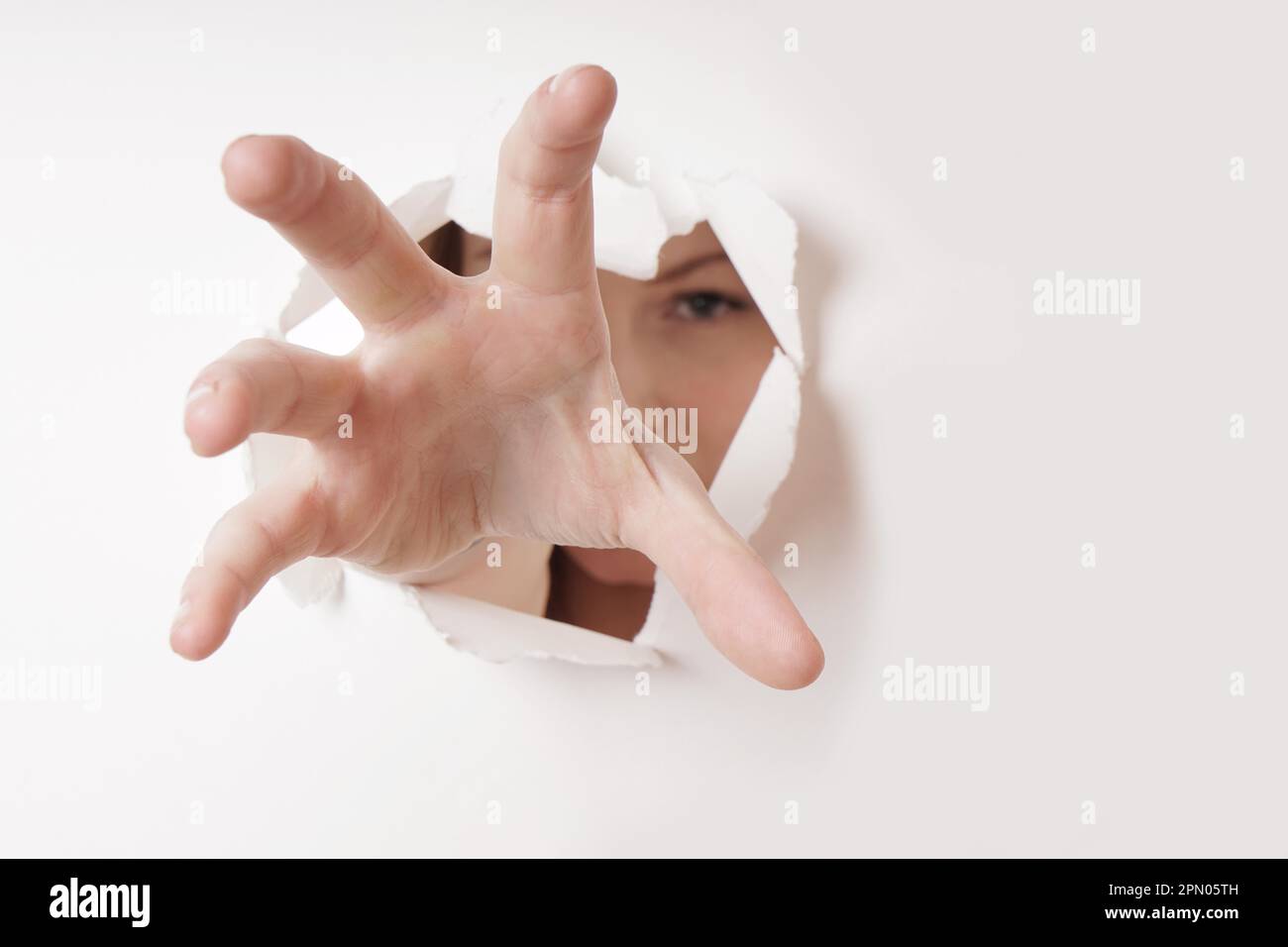 woman grabbing with hand through hole in paper wall Stock Photo - Alamy