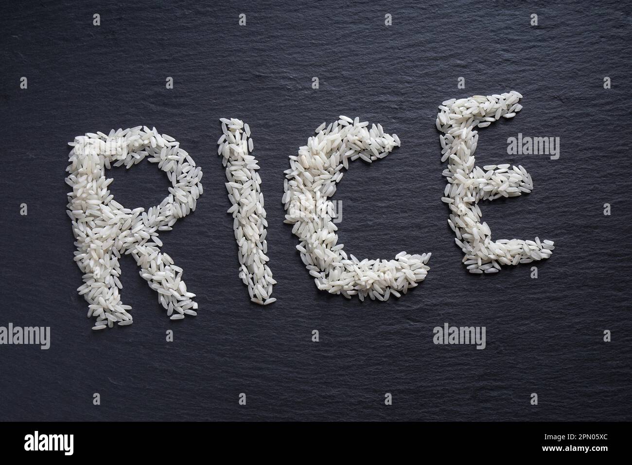 spelling out the word rice on black slate serving board Stock Photo - Alamy