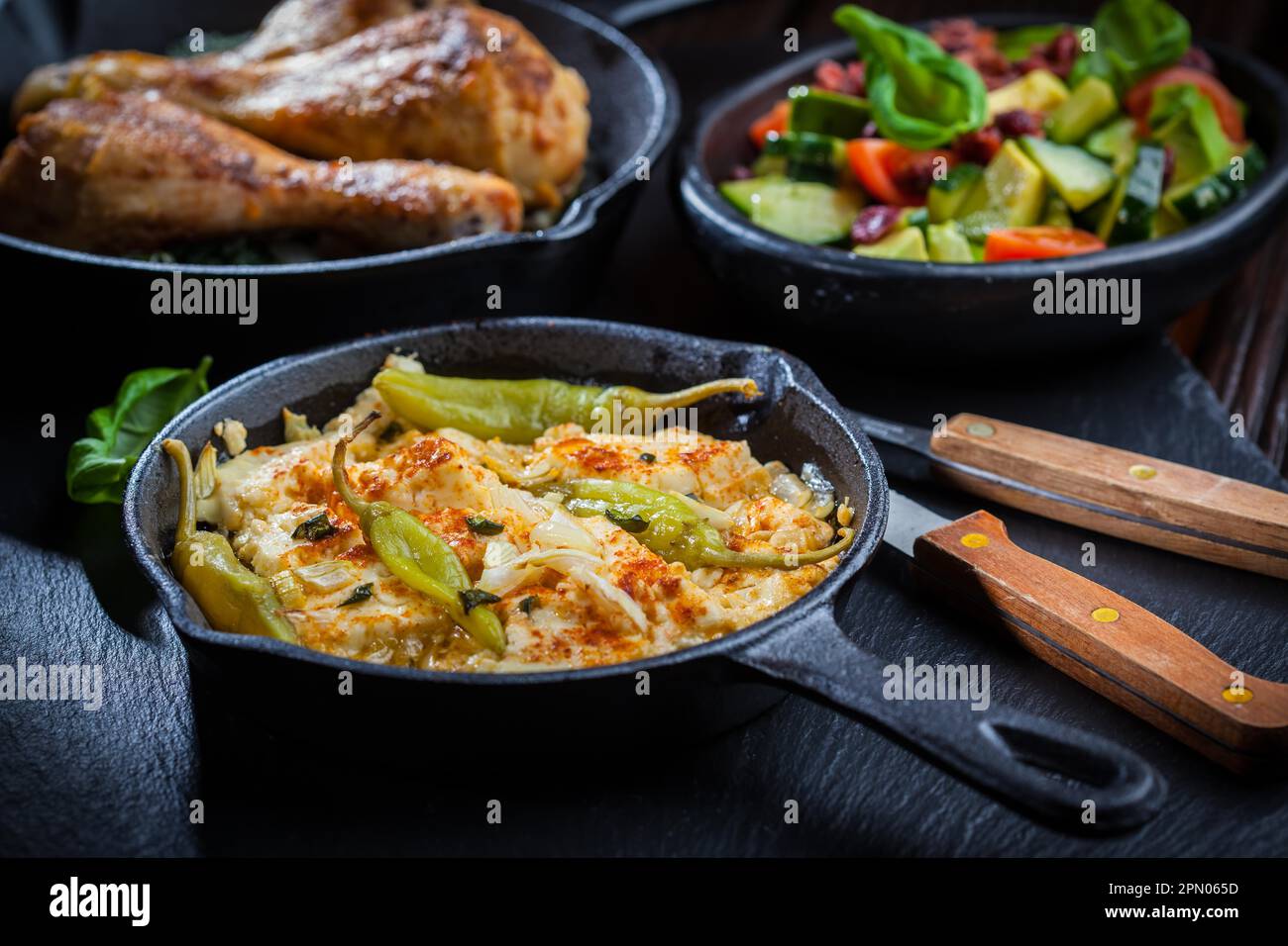Baked feta cheese with avocado salad and grilled chicken legs Stock ...