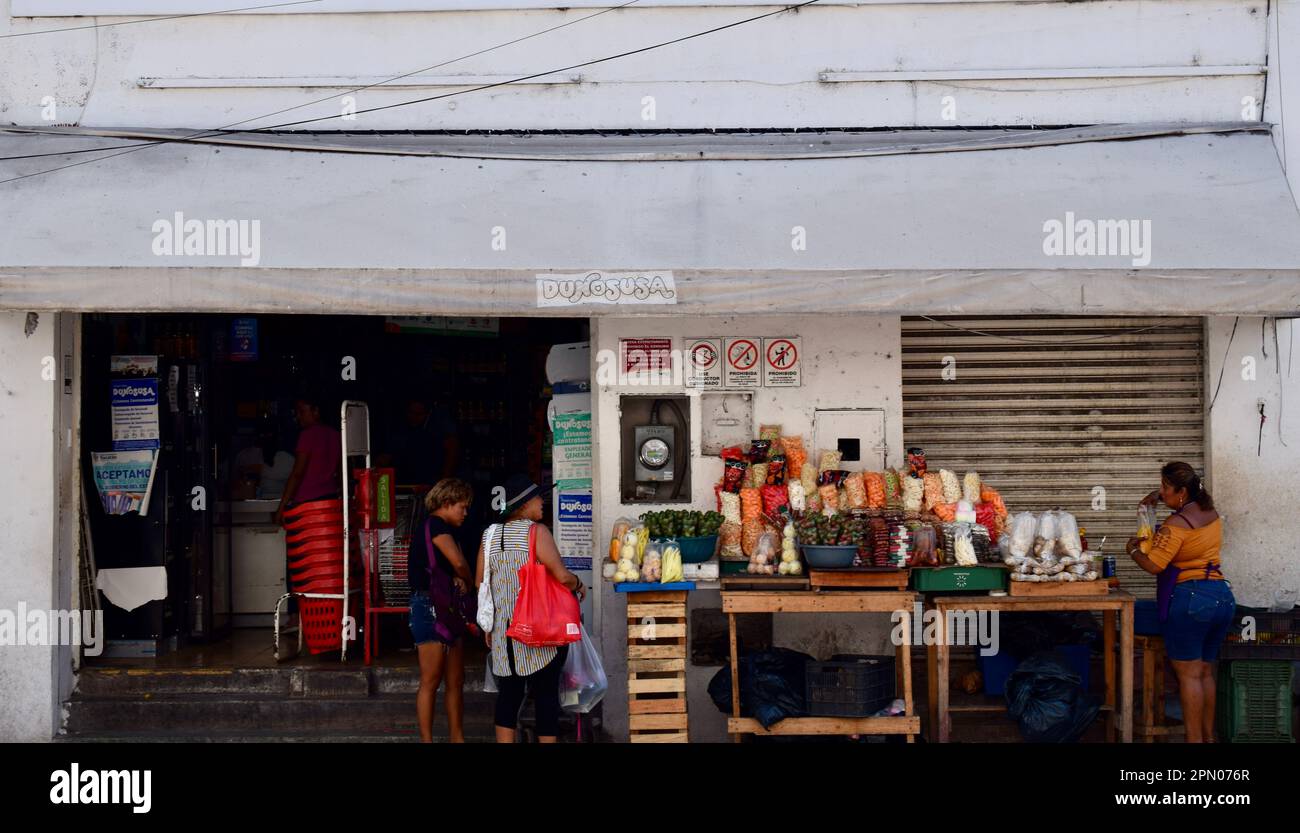 A fruit and snack vendor and some customers on a street in Merida ...
