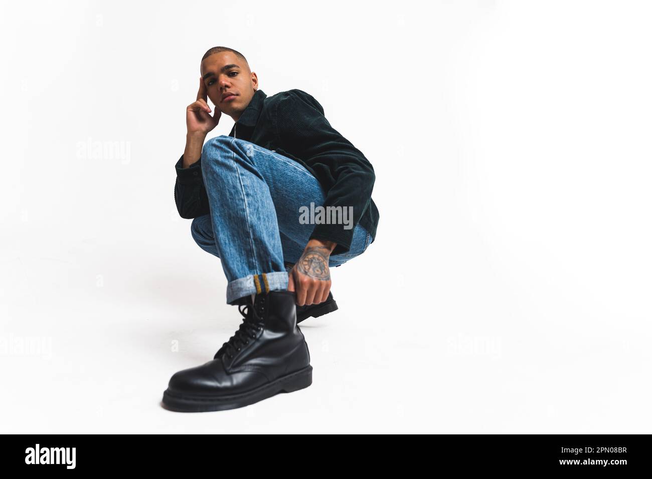 African American male fashion model crouching and posing to the camera ...