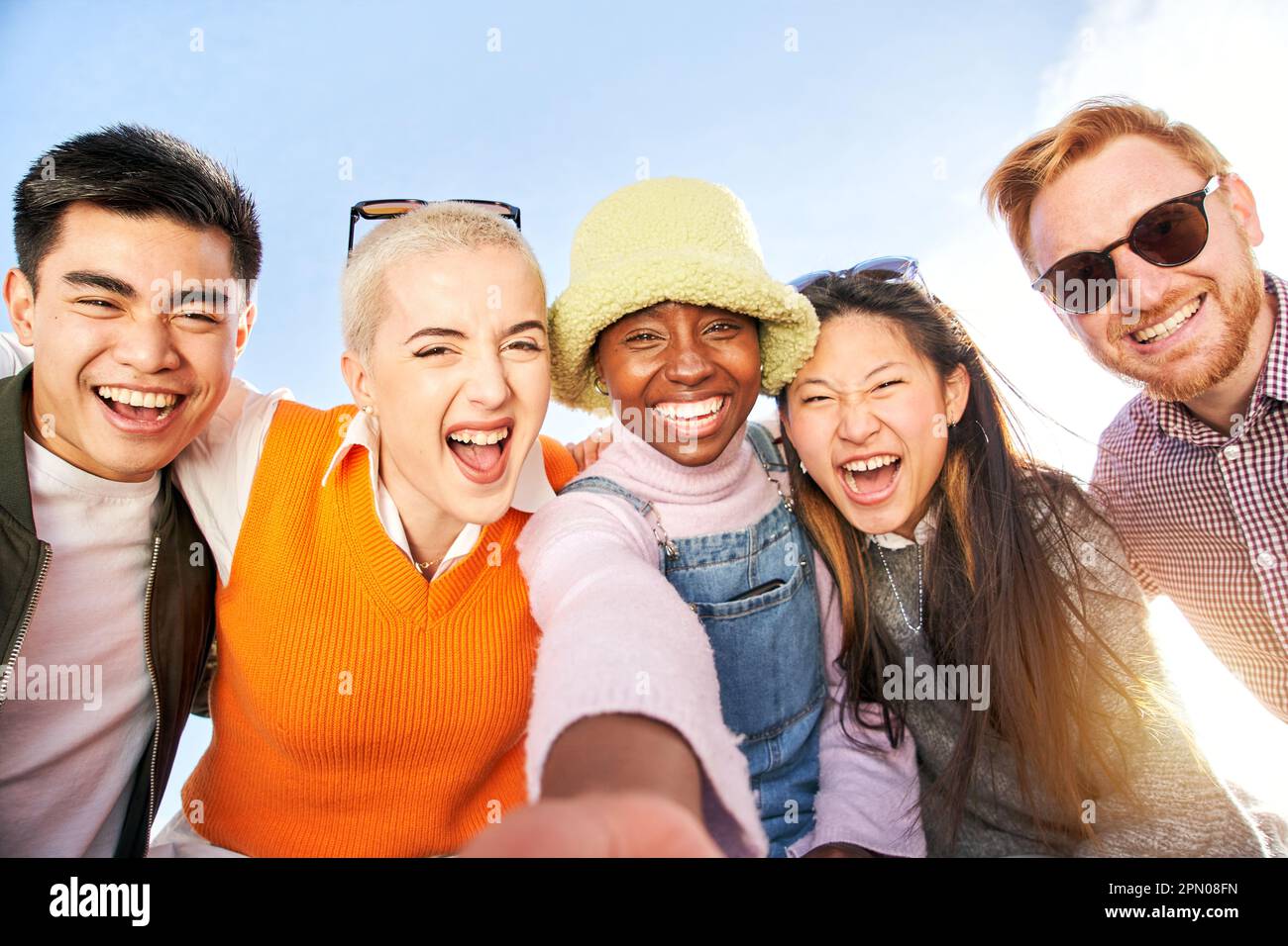 Smiling selfie of a cheerful group of multicultural friends looking at ...