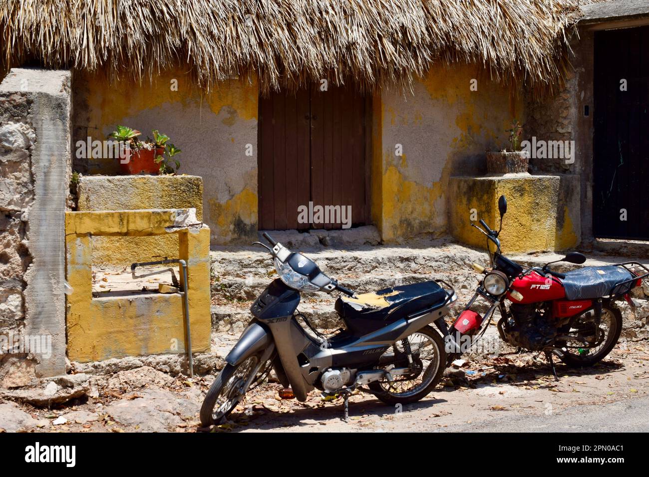 A traditional Mayan structure with a thatched roof with two motorcycles ...