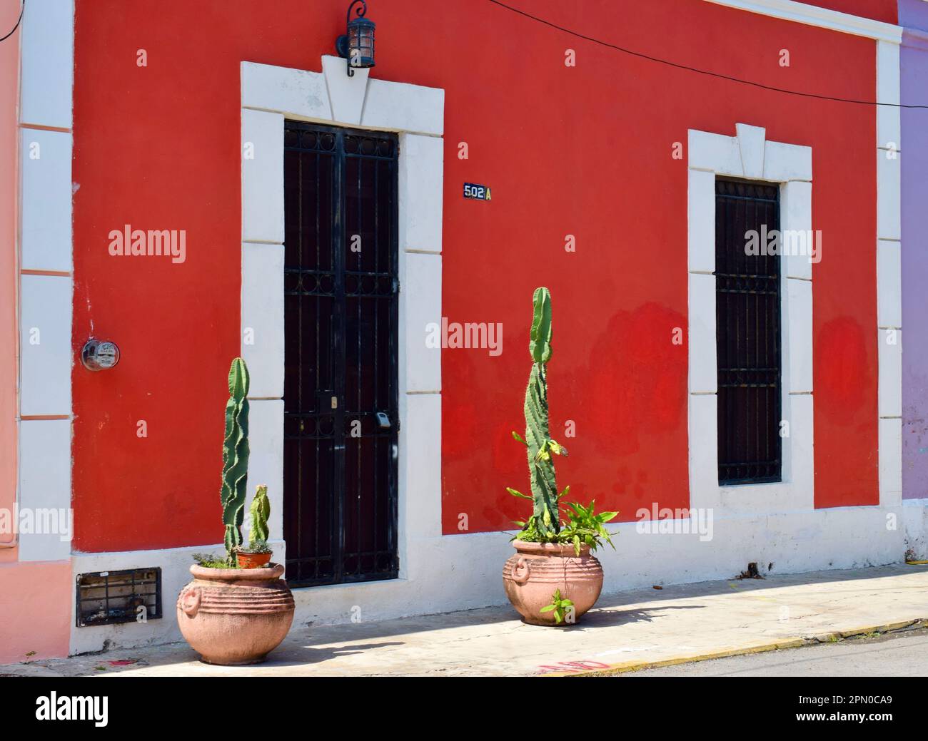 A beautifully restored building, painted in red, with two cacti beside ...